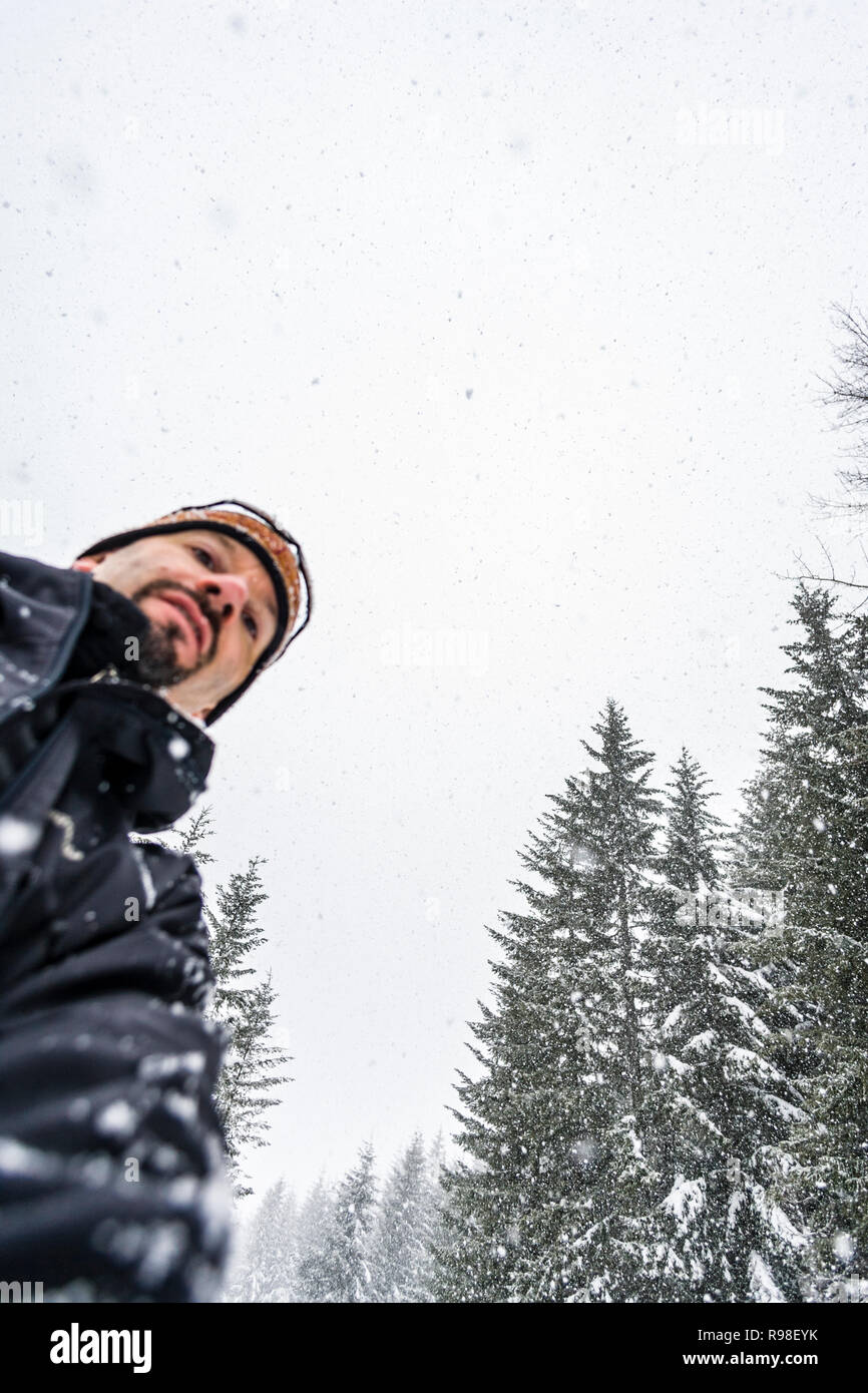 A man from a low angle with snow falling from the sky above him Stock ...