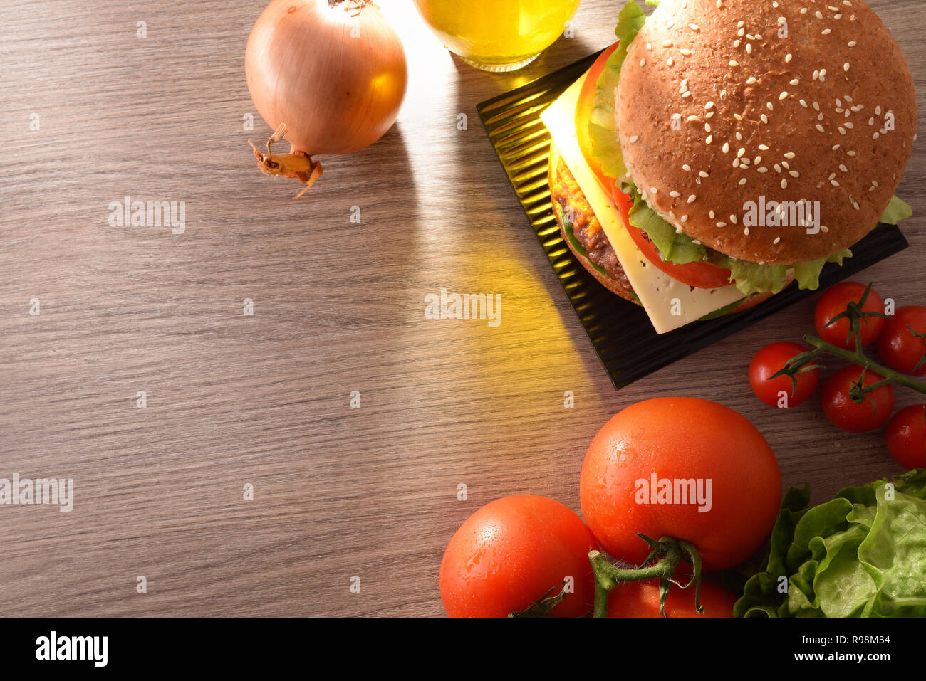 Homemade beef burger with vegetables on wooden table in kitchen. Top ...