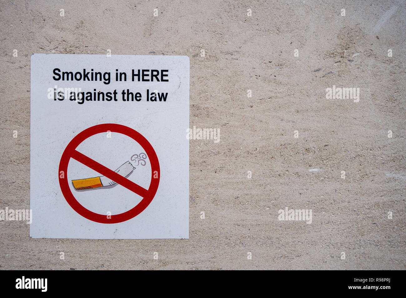 Smoking in HERE is against the law sign on the wall of an office block ...