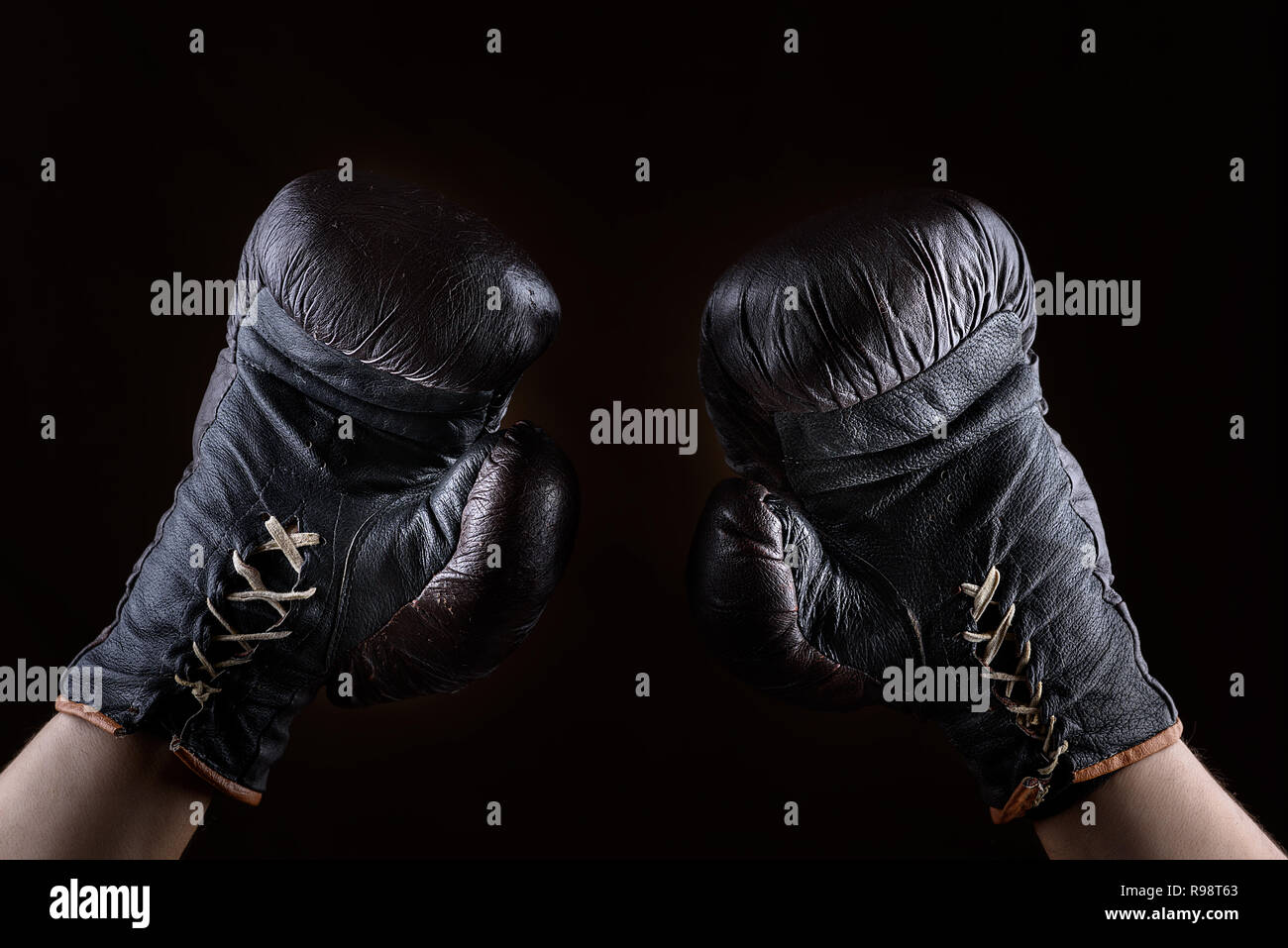 raised up arms of an athlete dressed in leather brown boxing gloves ...