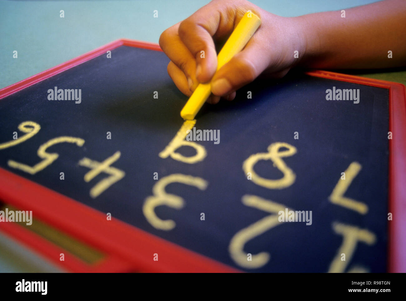 Child writing with yellow chalk numbers on black slate Stock Photo - Alamy
