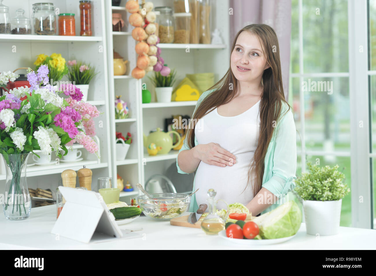 Happy pregnant woman cooking in the kitchen Stock Photo - Alamy