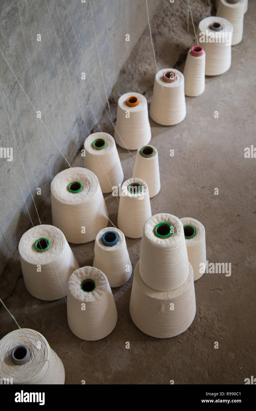 Cones of thread lined up on the floor of the weavers studio, Ecuador ...