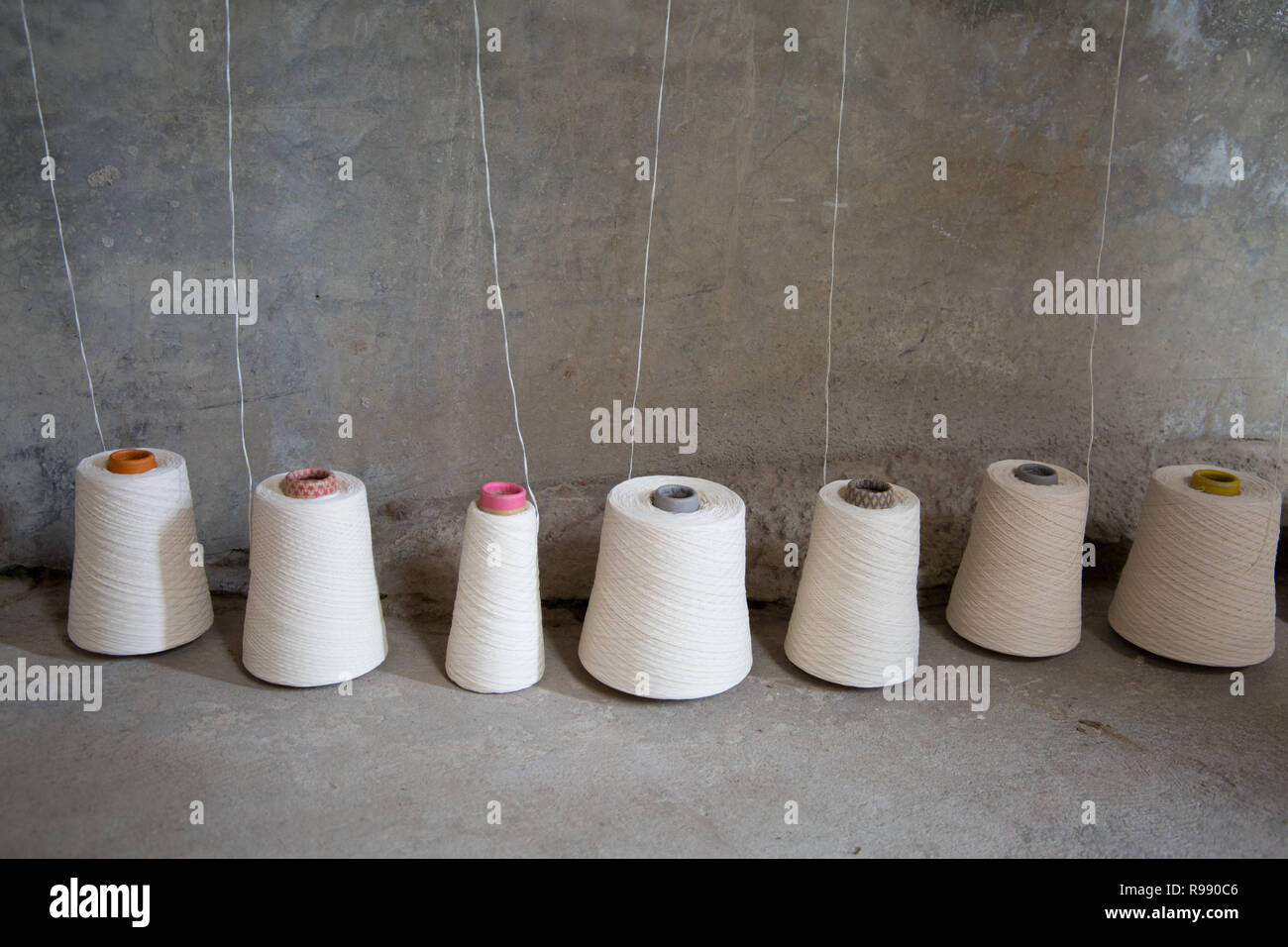 Cones of thread lined up on the floor of the weavers studio, Ecuador ...