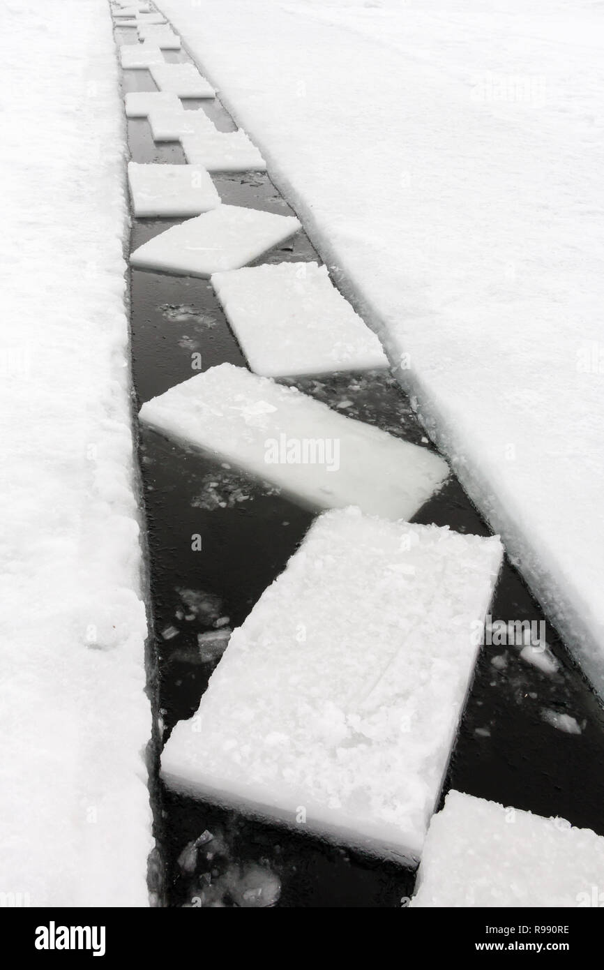 One meter long large ice cubes floating in an ice hole at a frozen lake ...