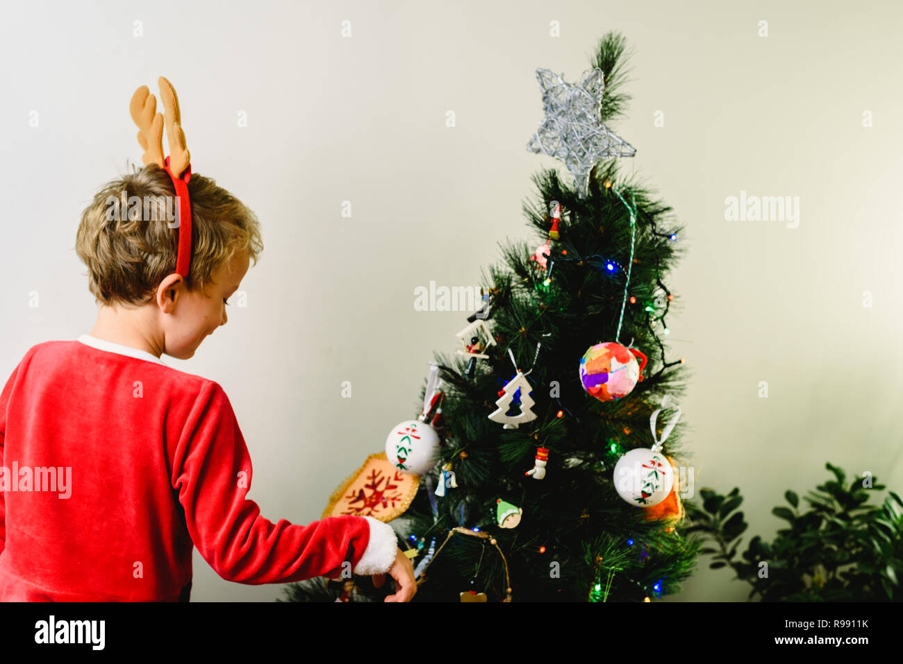 Child in Santa Claus costume, preparing the Christmas tree, back to ...
