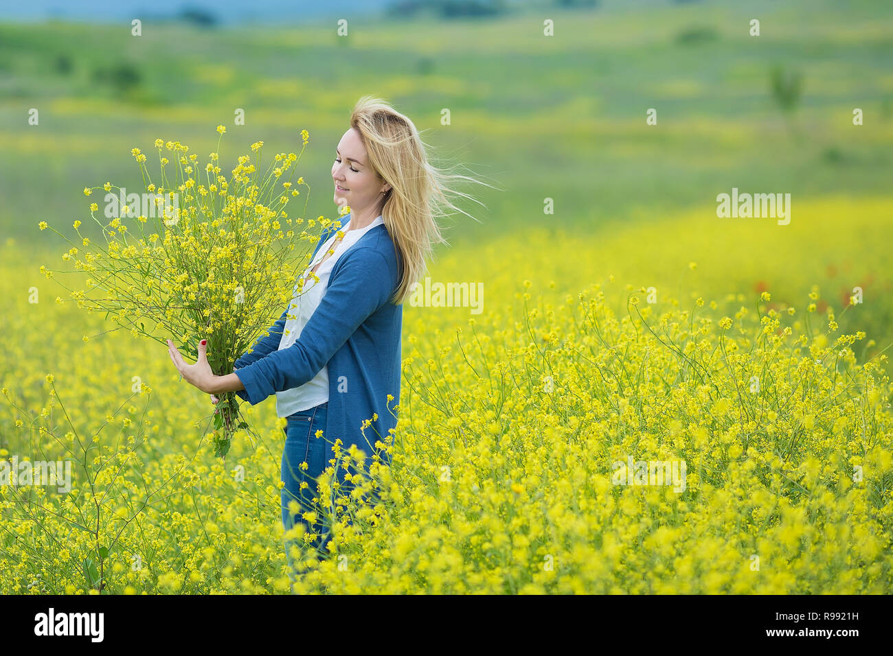 Genuine cute lady woman in meadow of yellow flowers sniffing flower ...