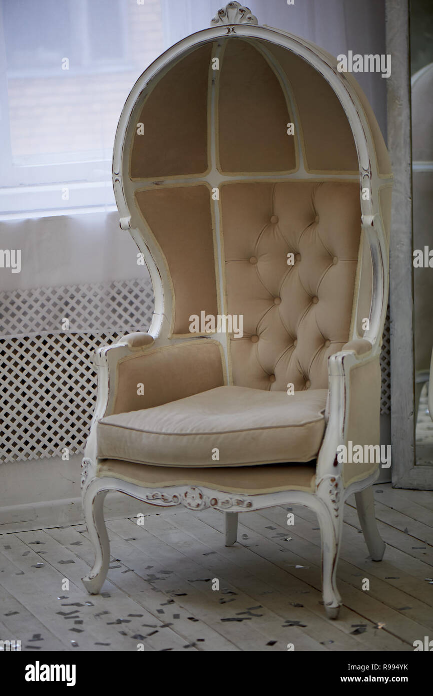 Massive old chair with light fabric upholstery and high closed back ...