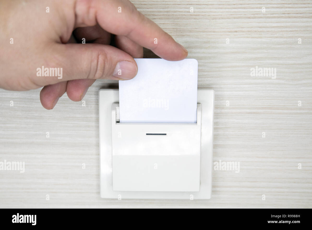 Closeup hand insert key card to opening light electronic in hotel room ...