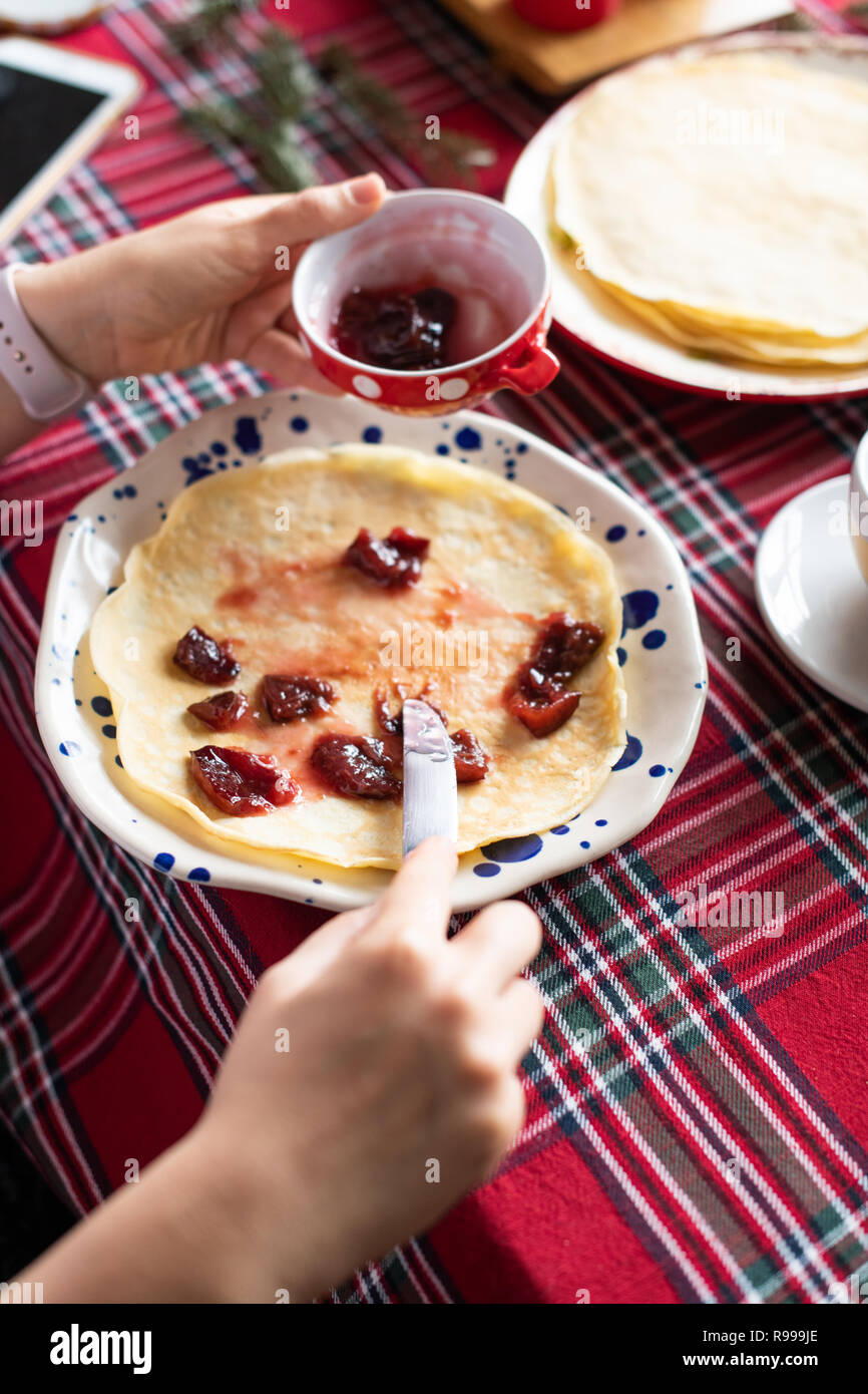 Woman spreading jam on french pancakes, hands shown, crepes with jam ...