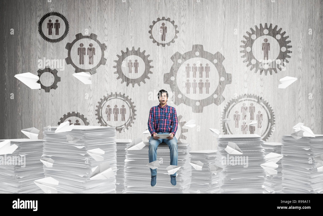 Attractive man sitting on pile of paper documents Stock Photo - Alamy
