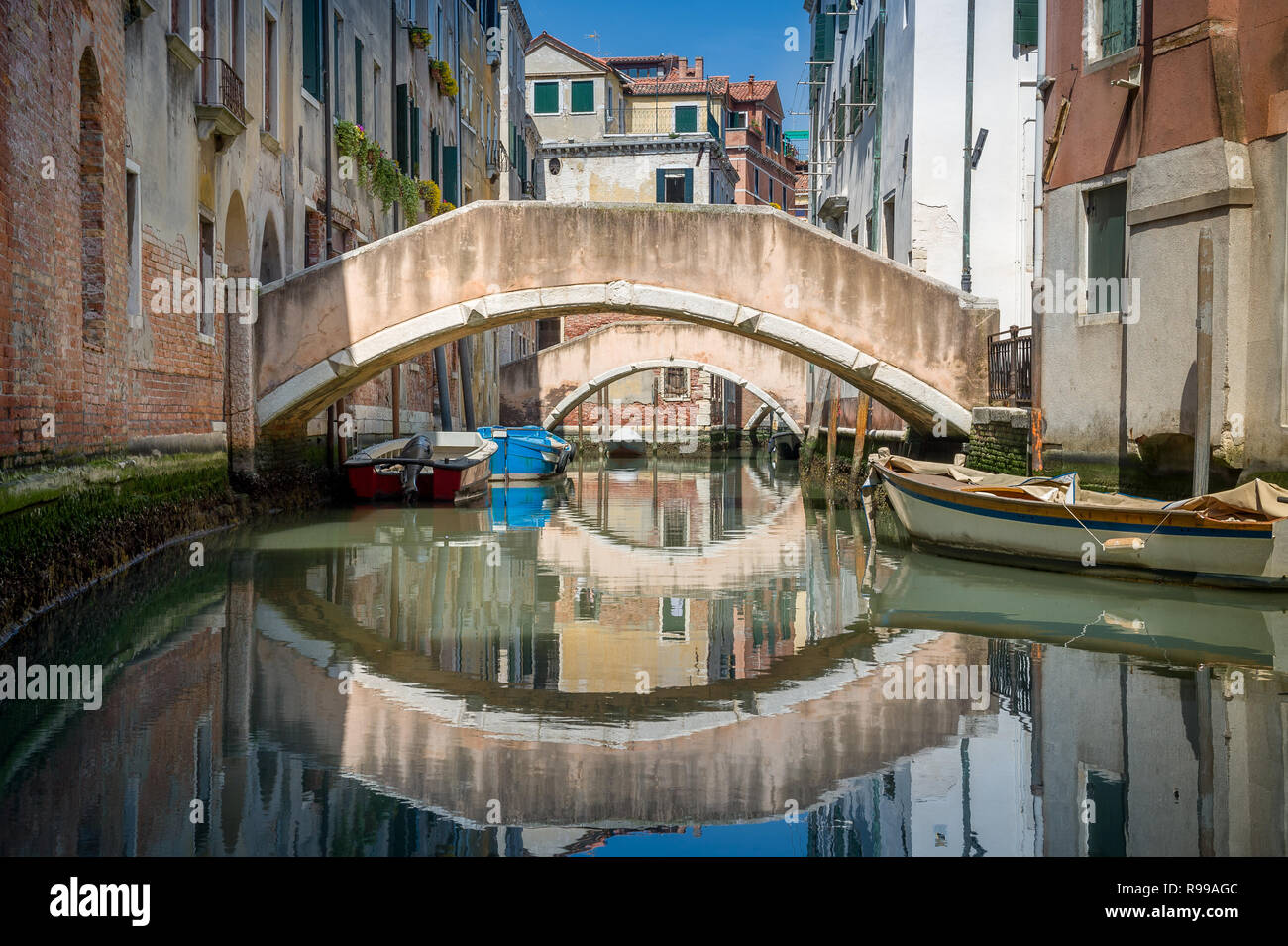 Curved bridges with beautiful reflections on the channel water. Venice ...
