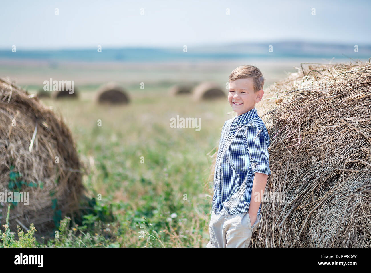 Attractive boy sitting on a haystack and smiling Stock Photo - Alamy