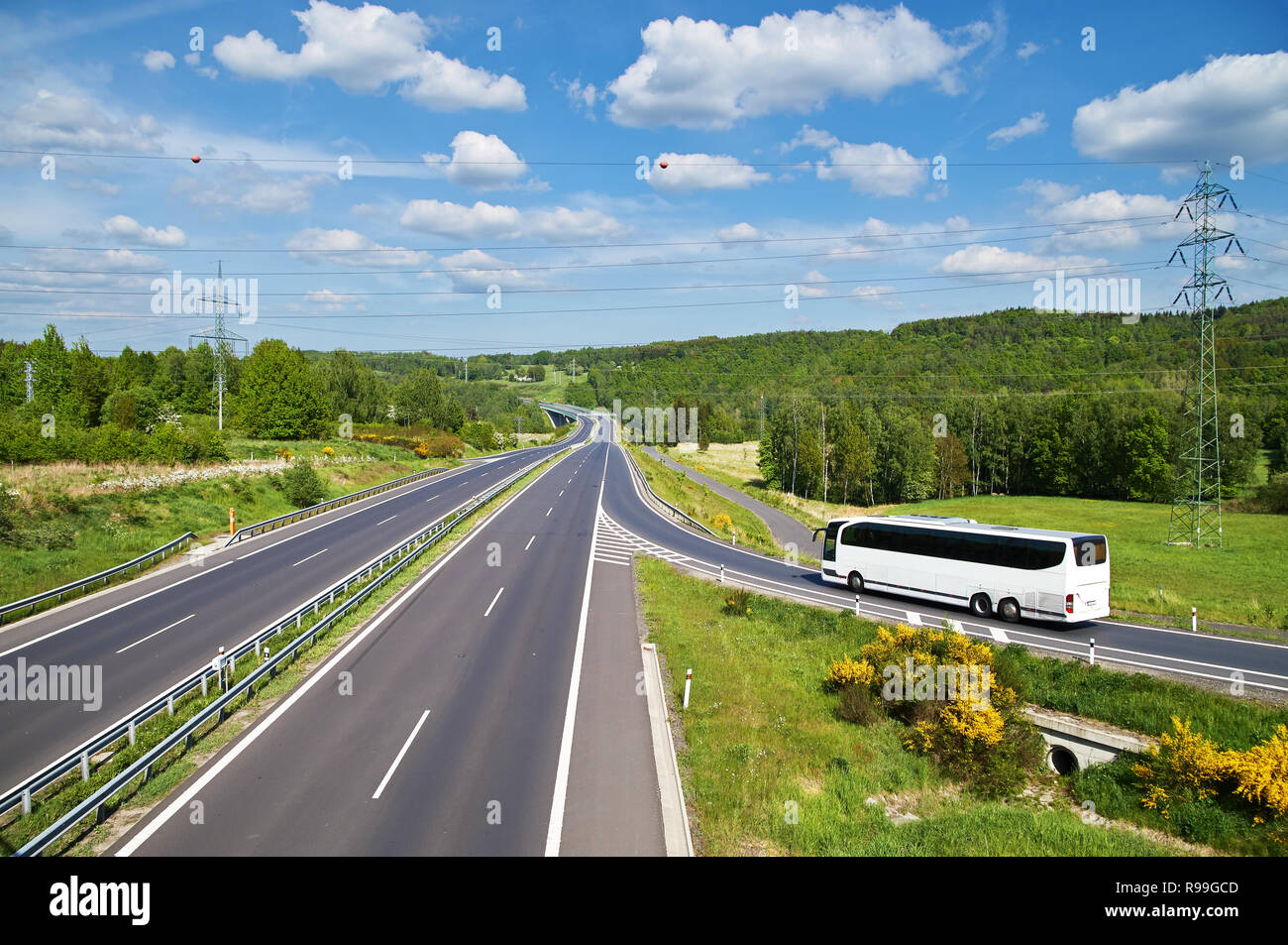 White Bus entering on an empty asphalt highway in the landscape. High ...