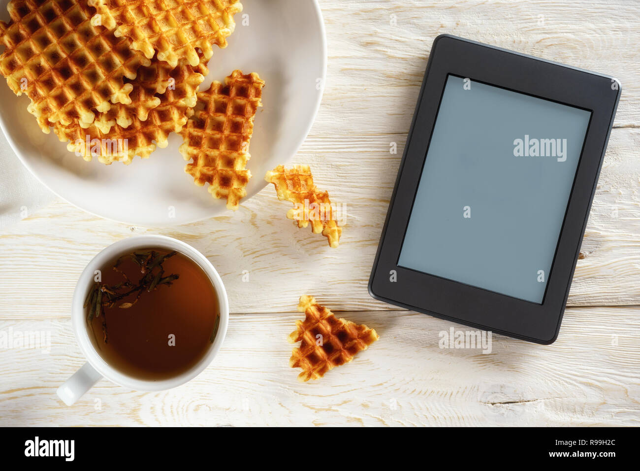 Cup of tea, waffle and ebook on white wooden background Stock Photo - Alamy