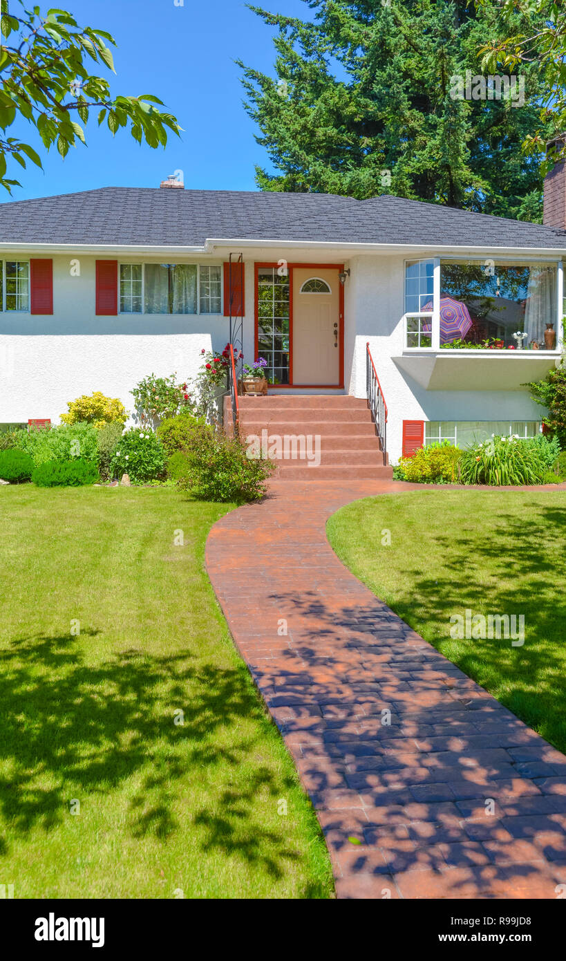 Average family house with green lawn and trees in front on blue sky ...