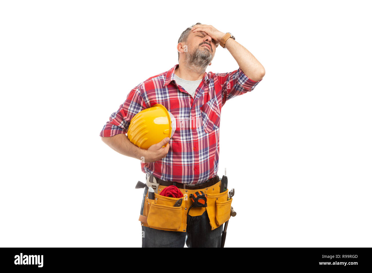 Builder with migraine holding yellow helmet in hand and touching head ...