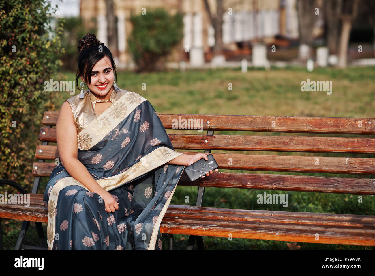 Elegant brunette south asian indian girl in saree sitting on bench with ...