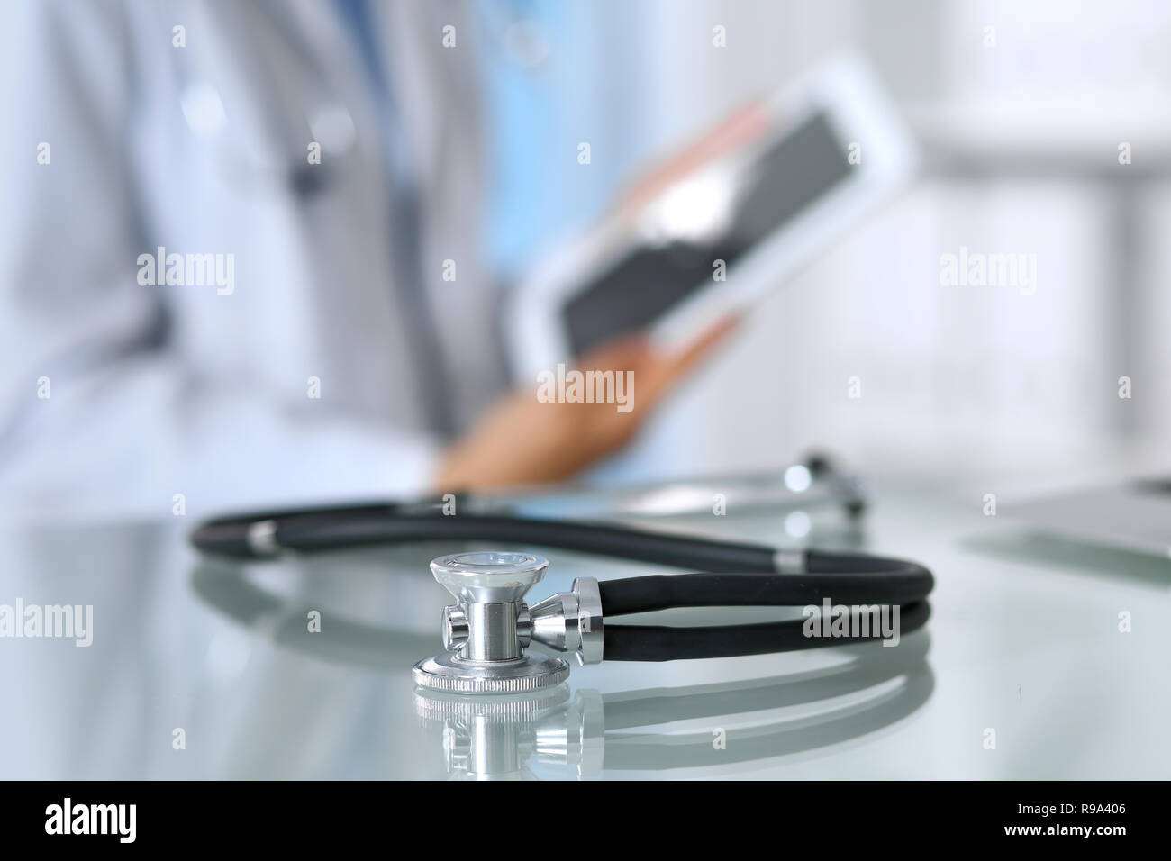 Stethoscope lying on glass desk with laptop computer at busy physician ...
