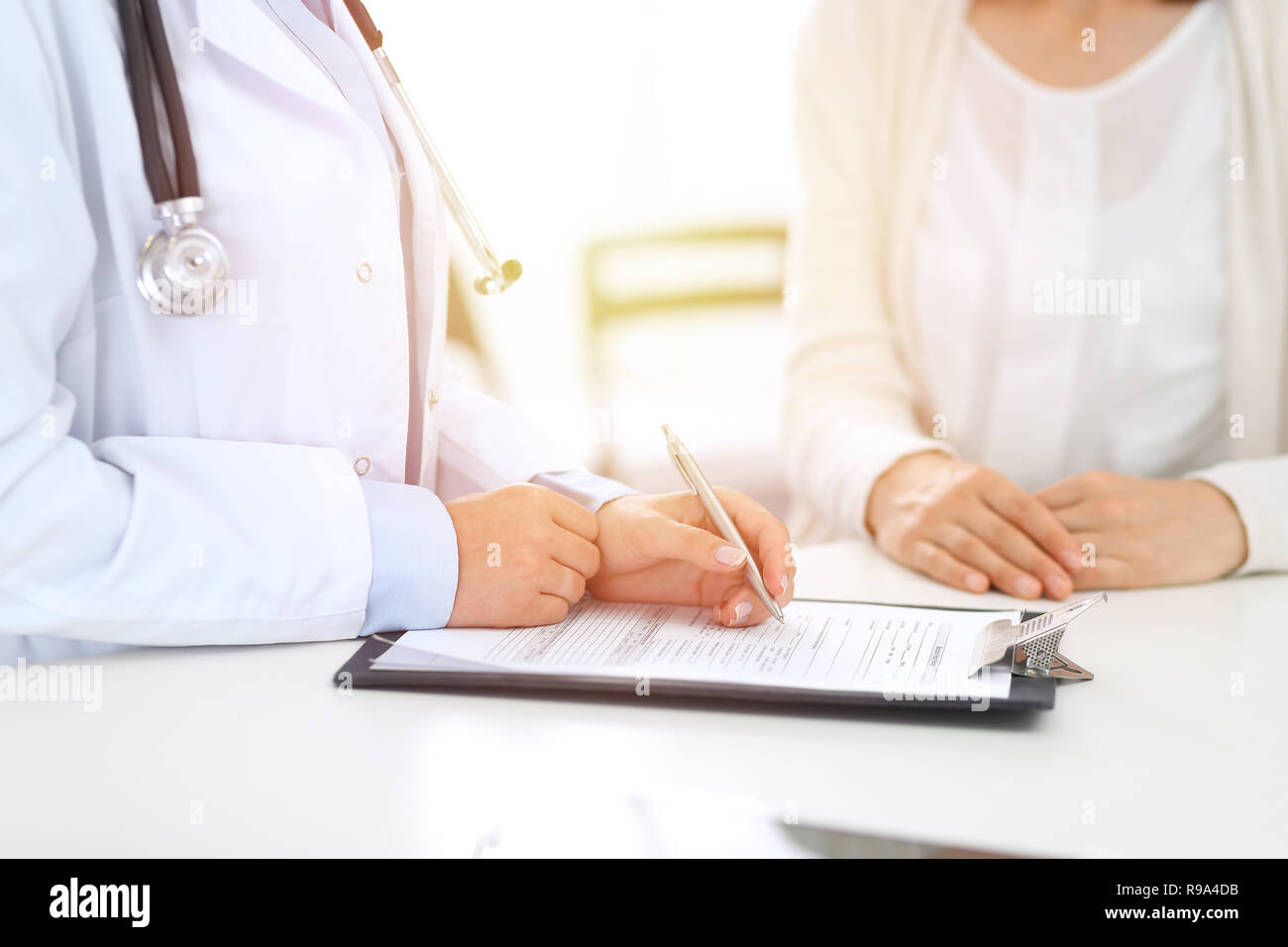Unknown doctor and female patient discussing something while standing ...