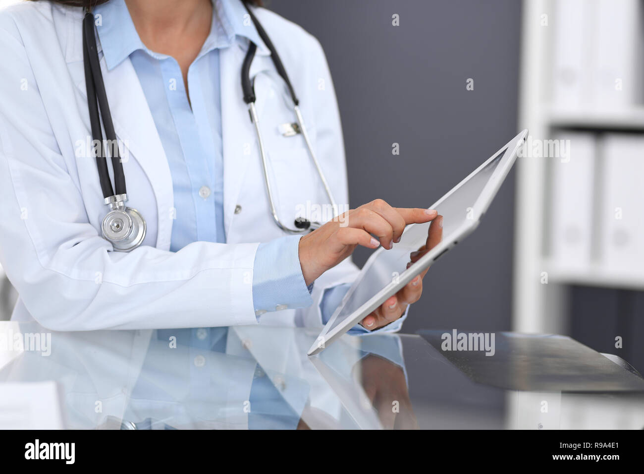 Close-up of female physician hands using digital tablet while sitting ...