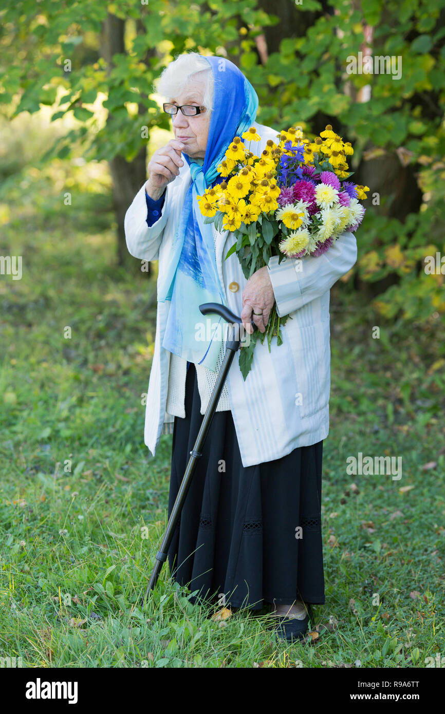 grandmother with a cane and flowers on the background of trees Stock ...