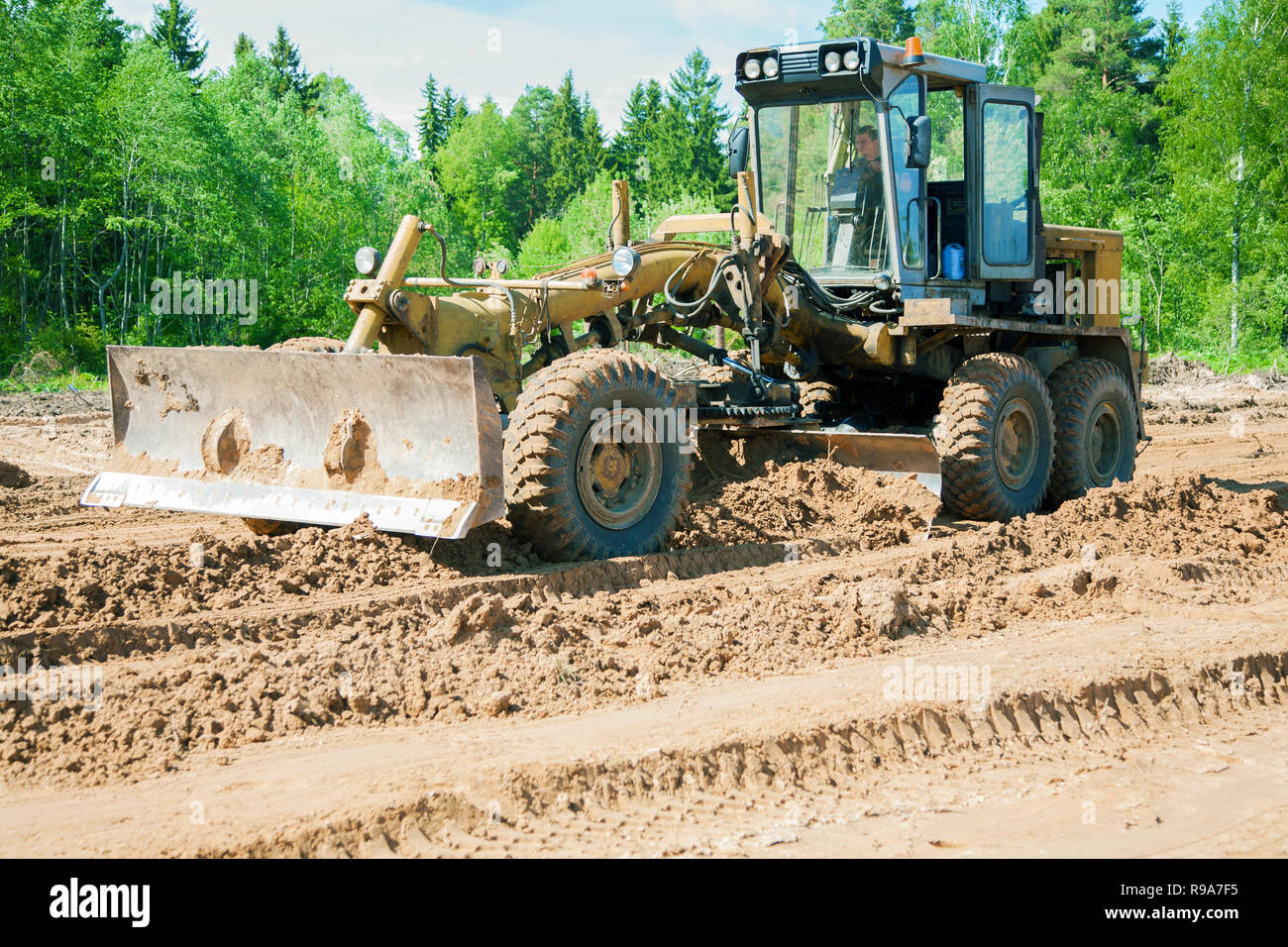 The grader clears away a ground In the afternoon Stock Photo - Alamy