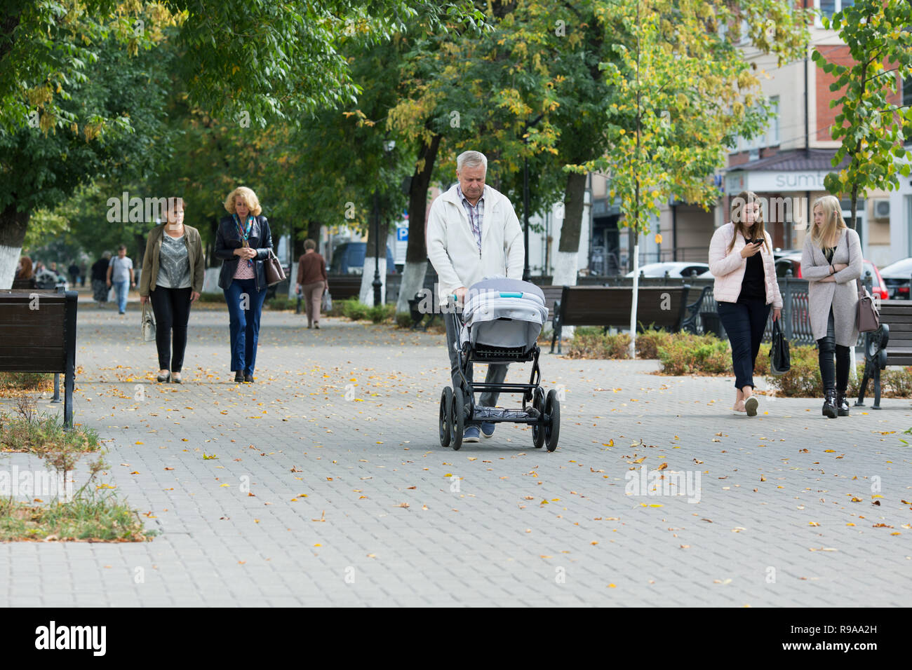 granddad with a stroller strolls down the city street in the fall Stock ...