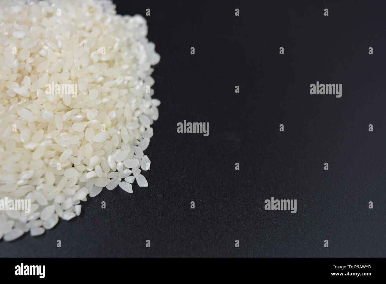 Beautiful polished loose white round rice on a black background, rice ...