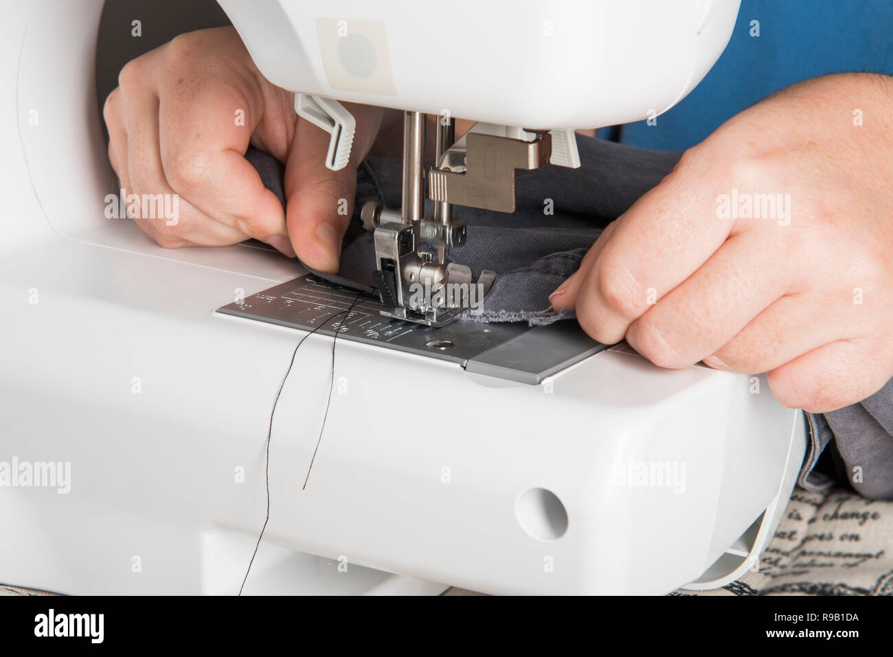 A Woman Using a modern Sewing Machine to repair clothing Stock Photo ...
