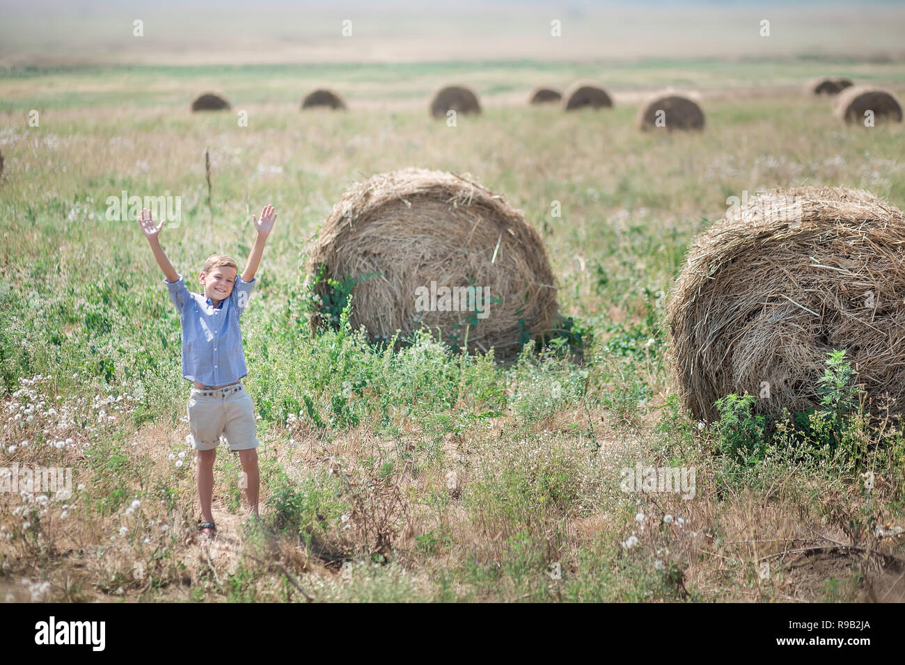 Attractive boy sitting on a haystack and smiling Stock Photo - Alamy