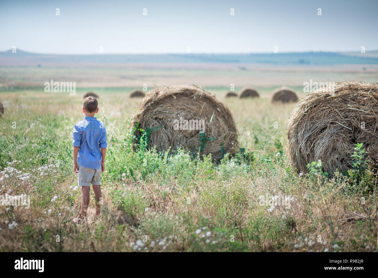 Attractive boy sitting on a haystack and smiling Stock Photo - Alamy