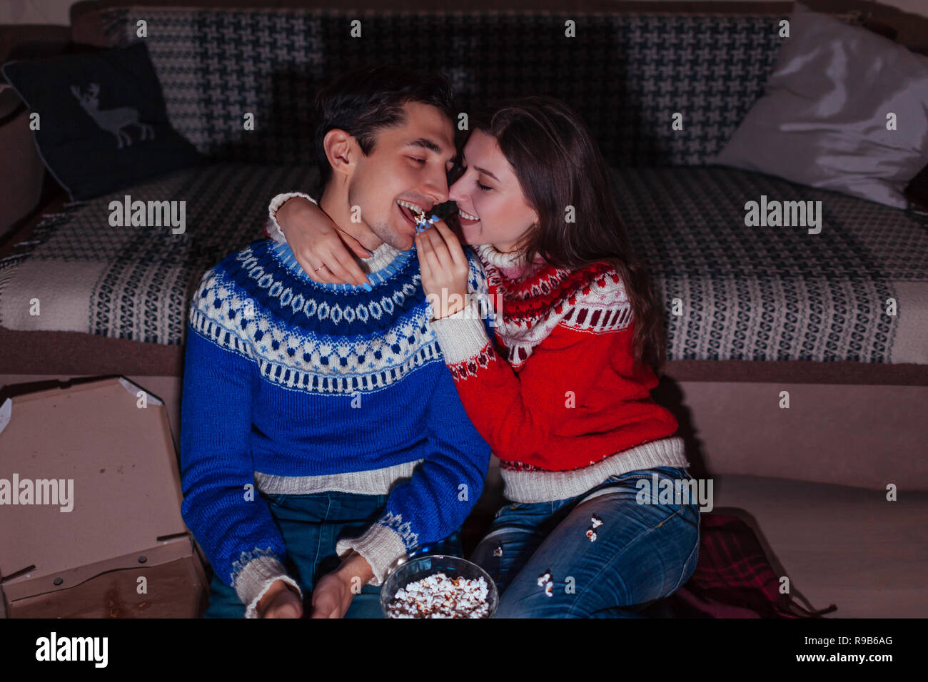 Young couple watching movie eating popcorn at home at night. Woman ...
