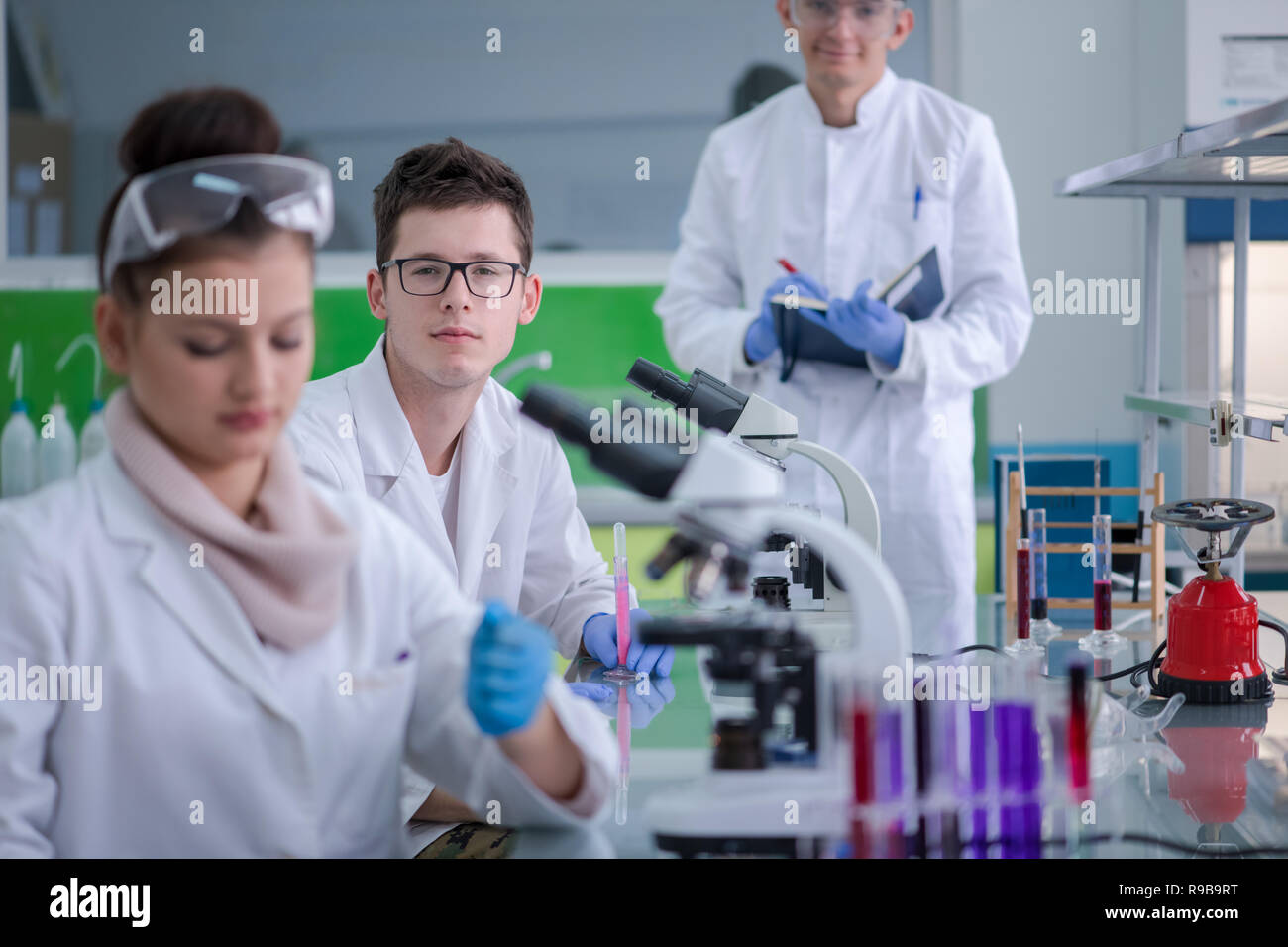 Group of young medical students doing research together in chemistry ...