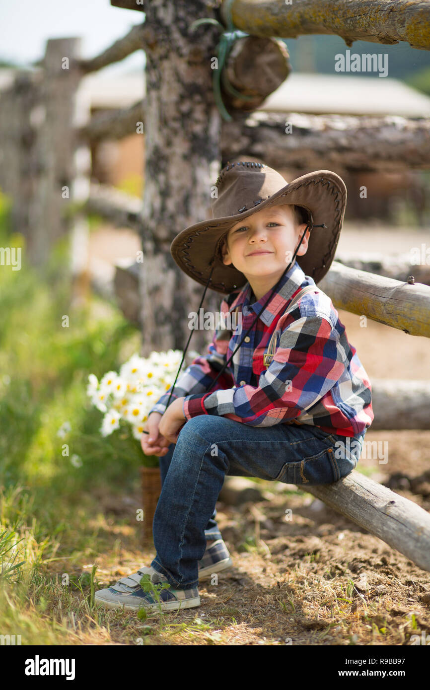 Cute fermer handsome boy cowboy in jeans enjoying summer day in village ...