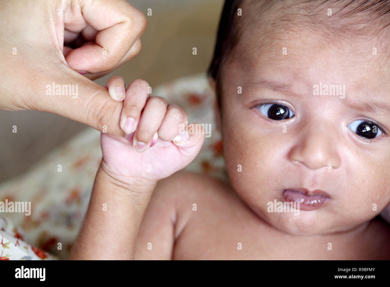 Newborn baby gripping mothers finger Stock Photo - Alamy