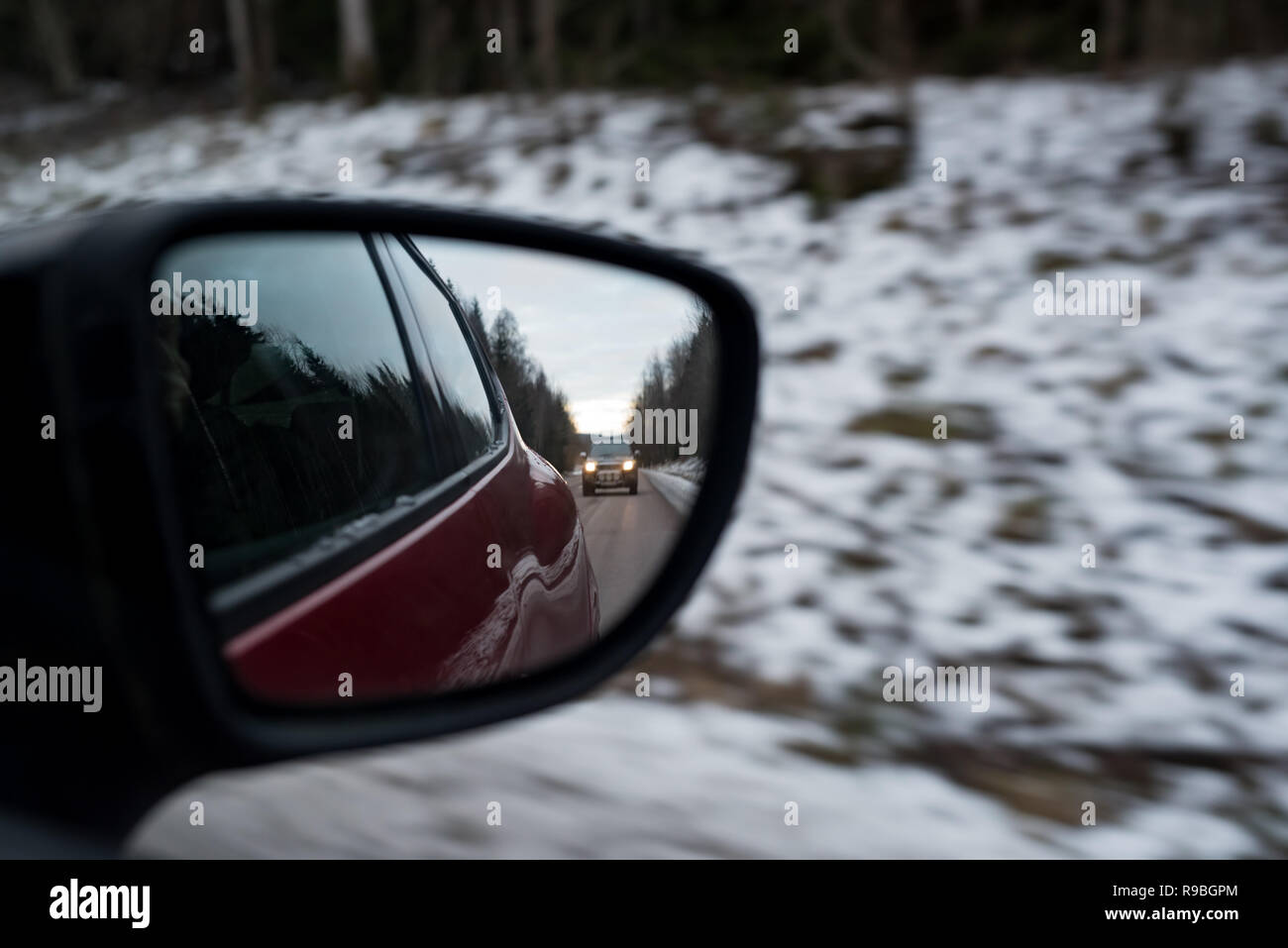 looking back in a side mirror at a car with its lights on Stock Photo ...