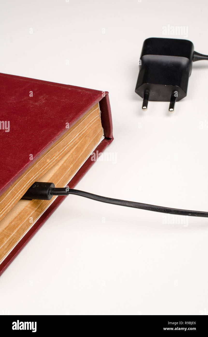 Old book with a battery charging cable, a concept of analog versus ...