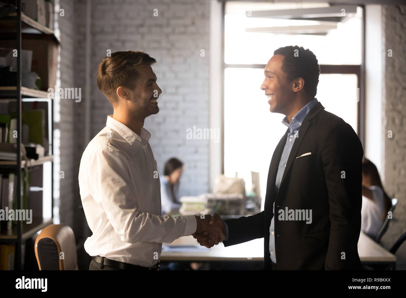 Friendly african and caucasian workers handshaking, welcoming ne Stock ...