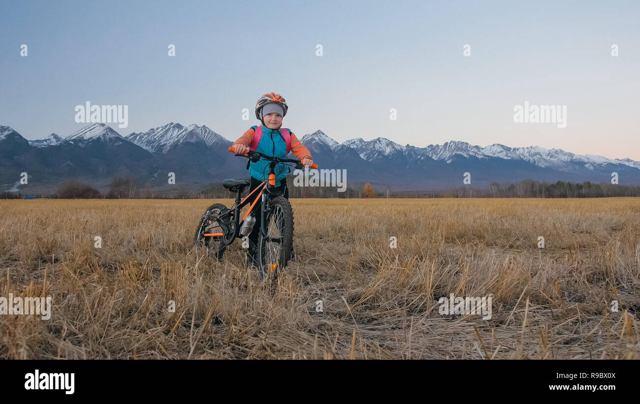 One caucasian children walk with bike in wheat field. Little girl ...