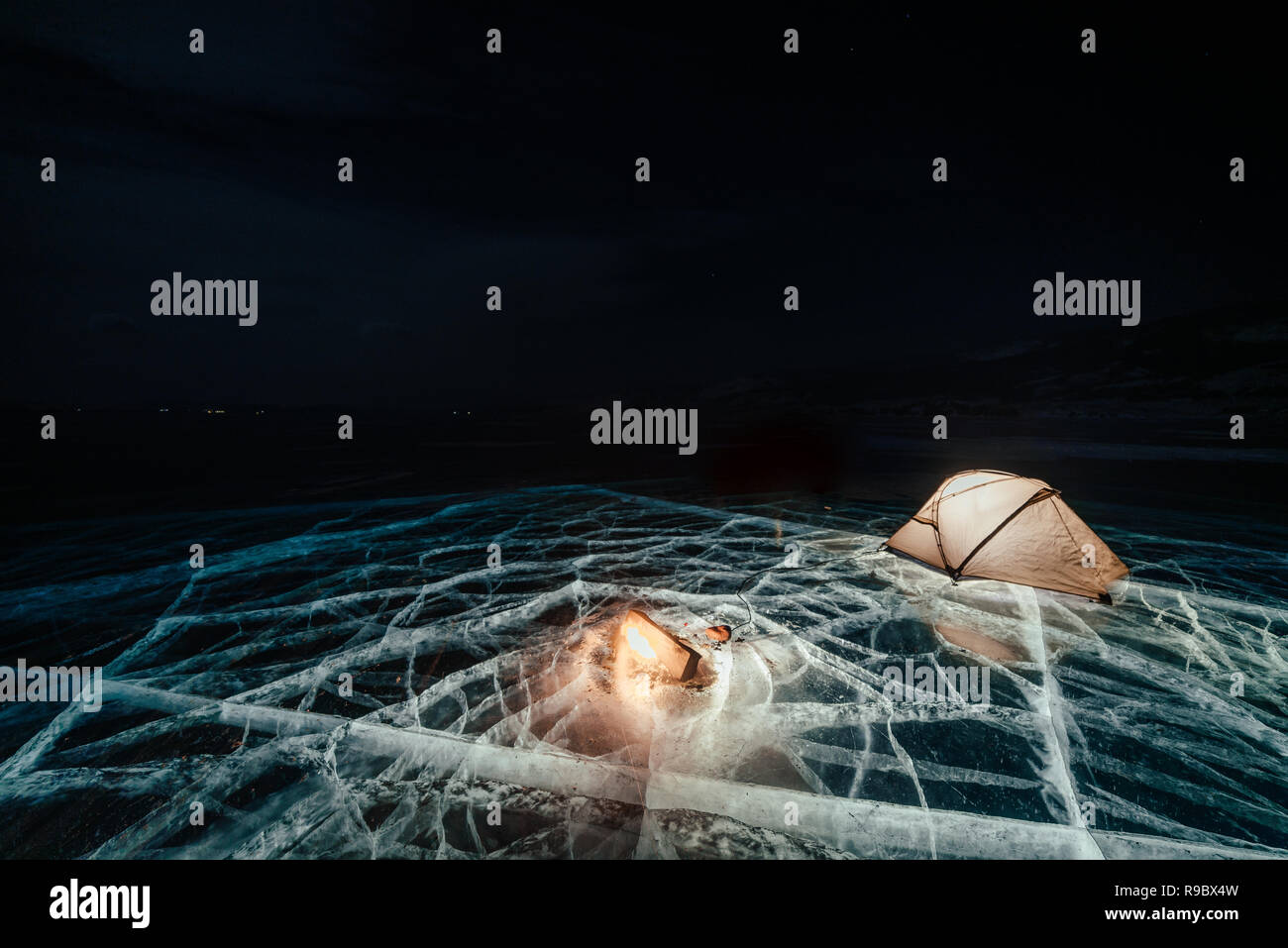 Fire on ice at night. Campground on ice. Tent stands next to bonfire ...