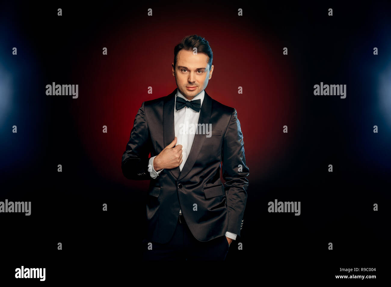 Professional showman wearing suit standing isolated on black and red ...