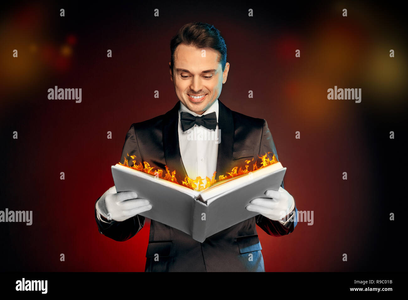 Professional magician wearing suit nd gloves standing isolated on black ...