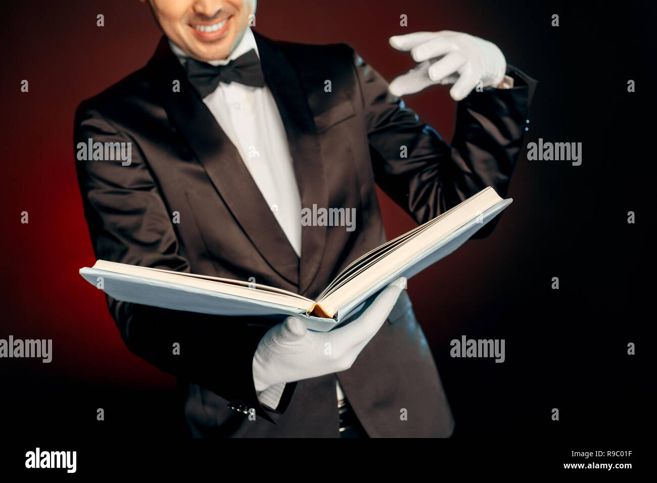 Professional magician wearing suit nd gloves standing isolated on black ...