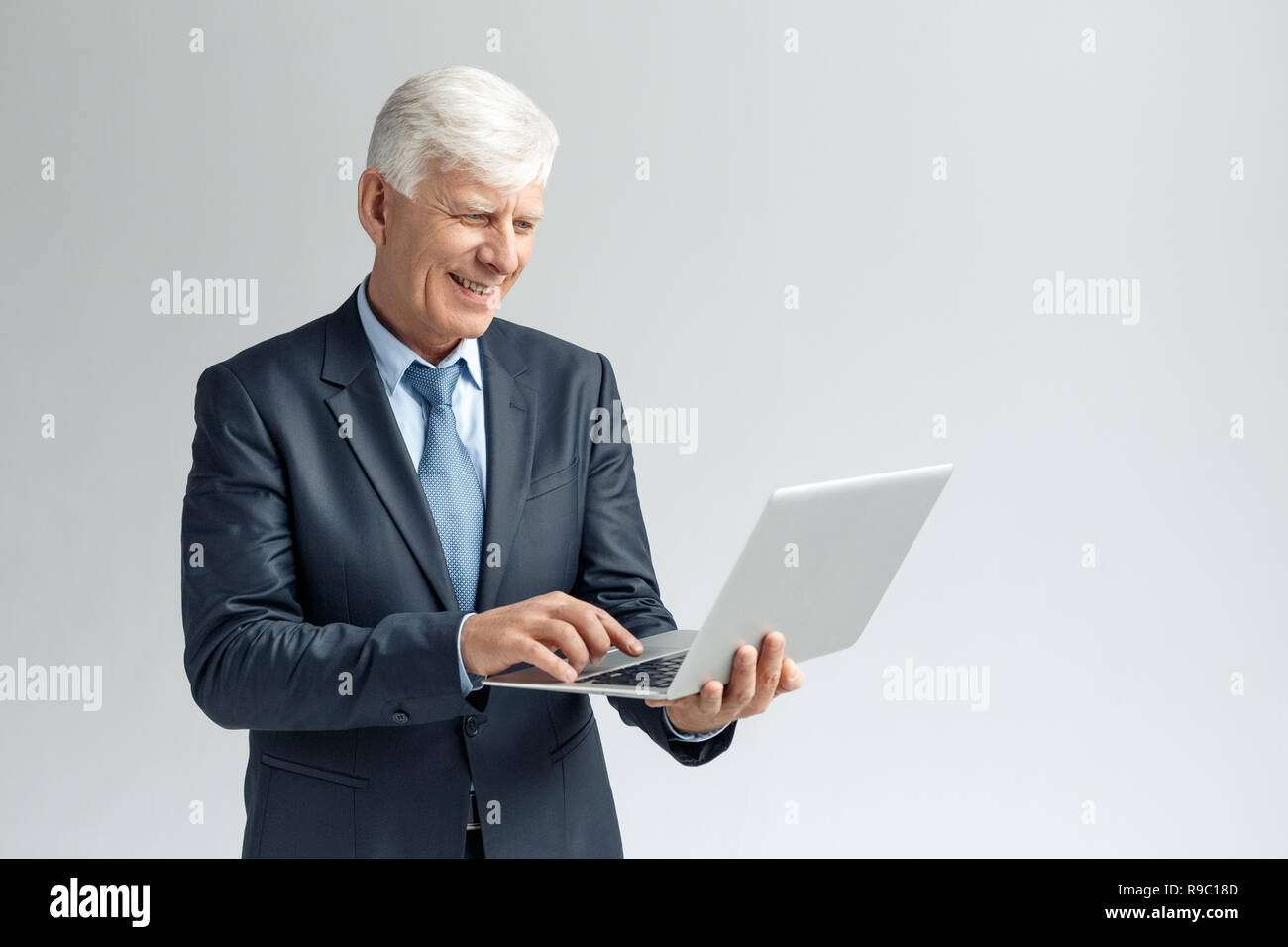 Senior business man studio standing isolated on gray wall holding ...