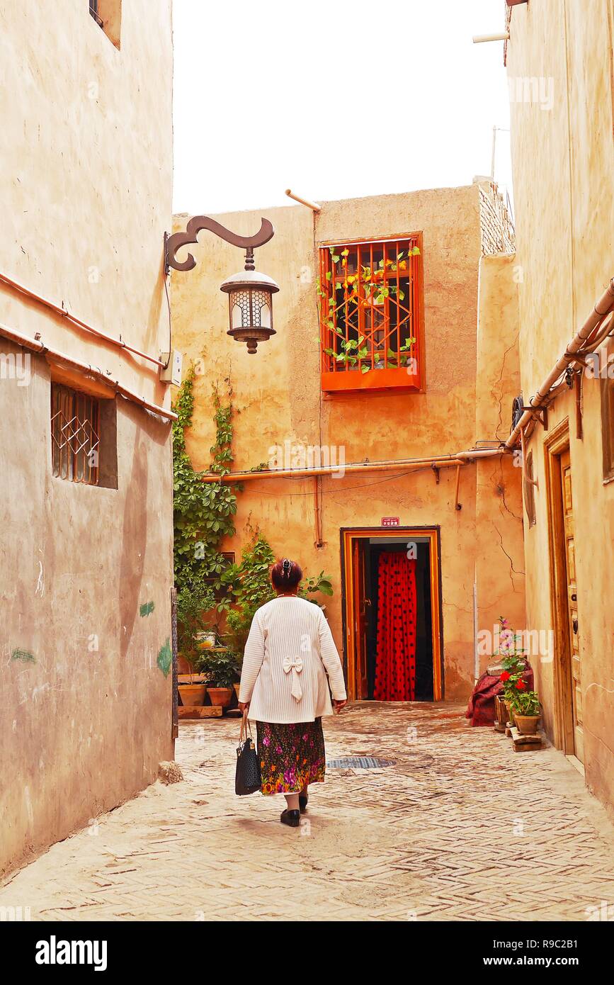 Street view of a Muslim woman walking down the street in small alley of ...