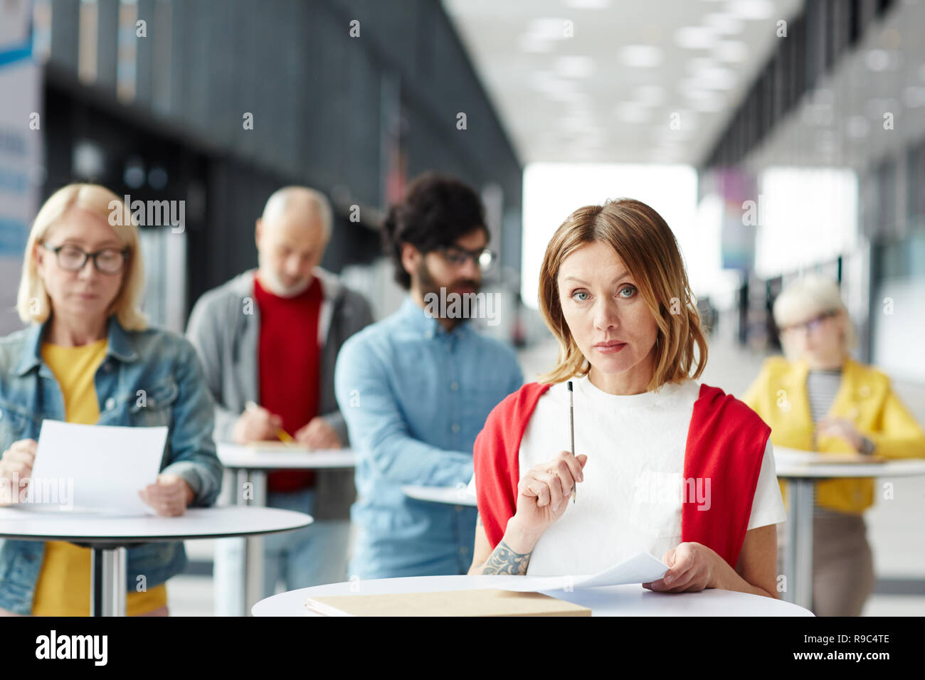 Pensive lady filling blank at high table Stock Photo - Alamy