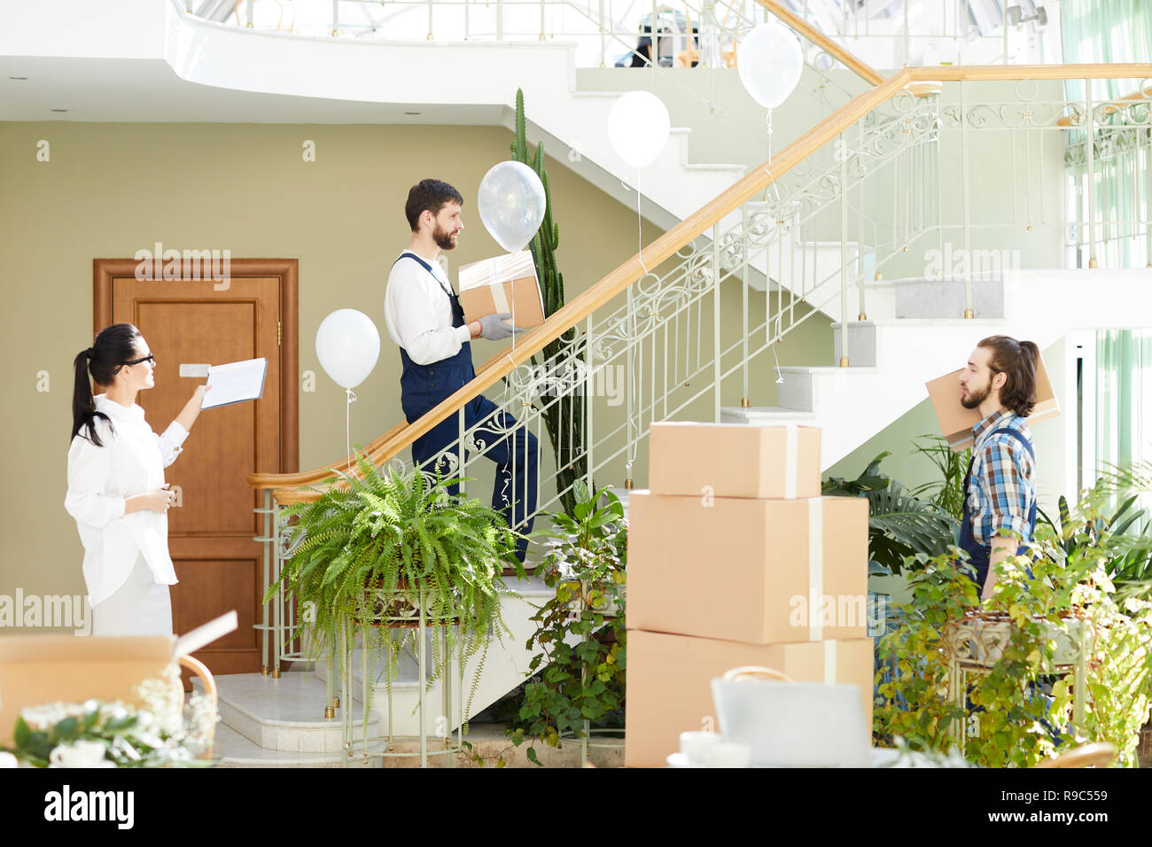 Stylish interior designer managing movers Stock Photo - Alamy