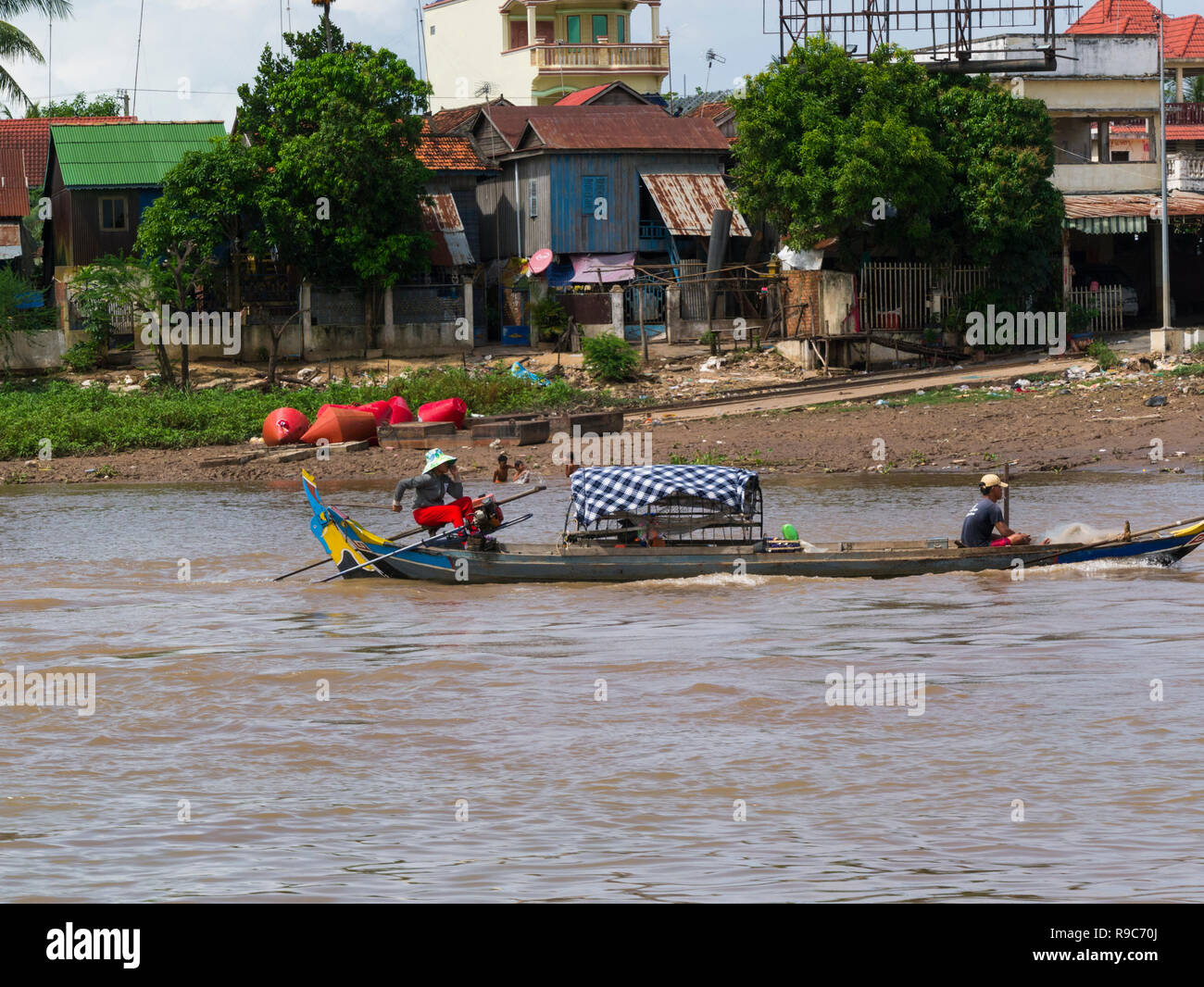 Two Cambodian men travelling along Mekong River in wooden river boat ...