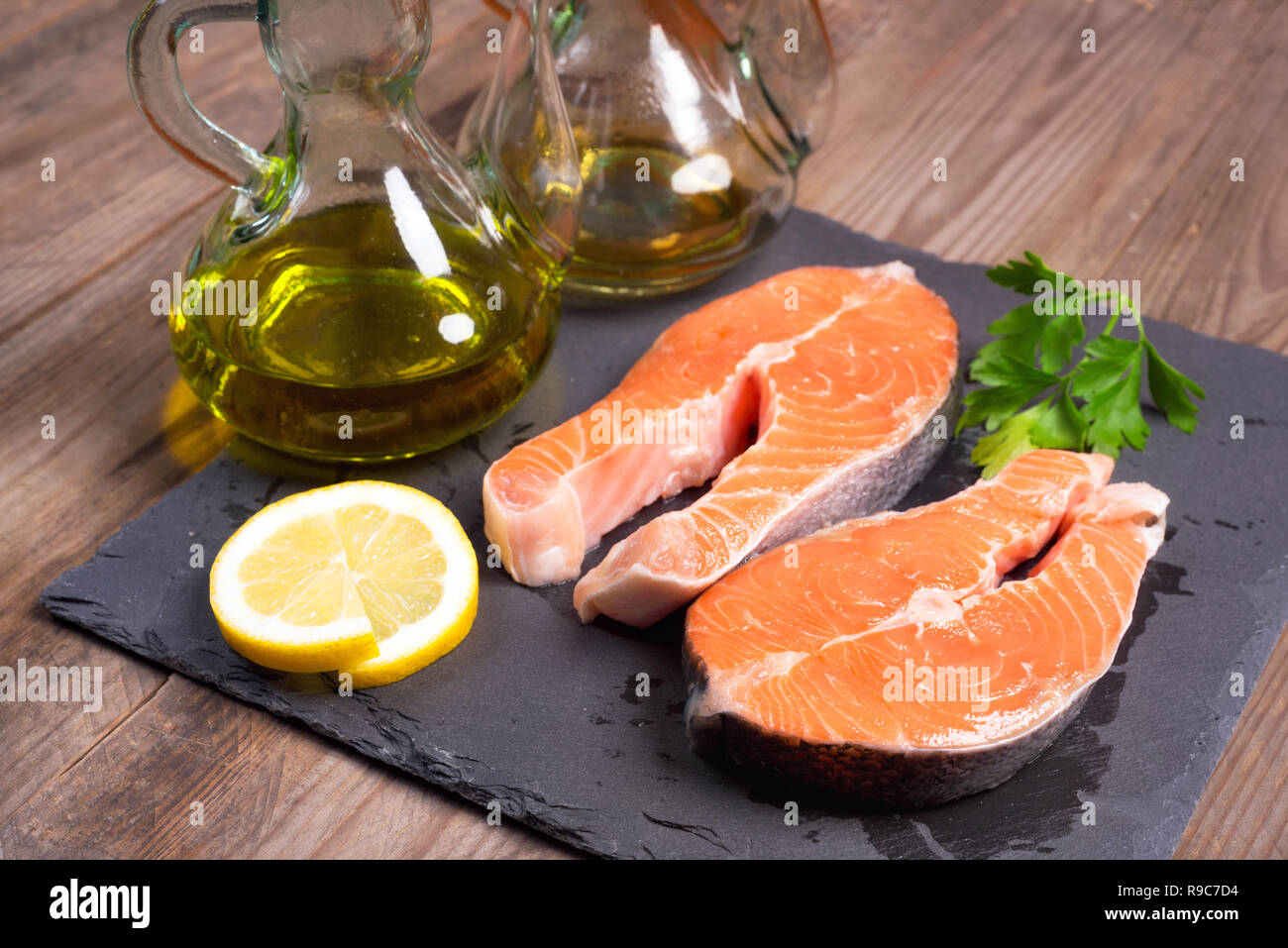 Delicious salmon steak on wooden table with lemon, parsley and olive ...
